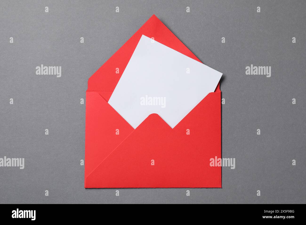 Blank sheet of paper in open letter envelope on grey background, top ...