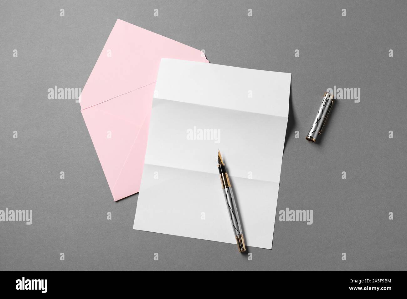 Blank sheet of paper, letter envelope and pen on grey background, top ...