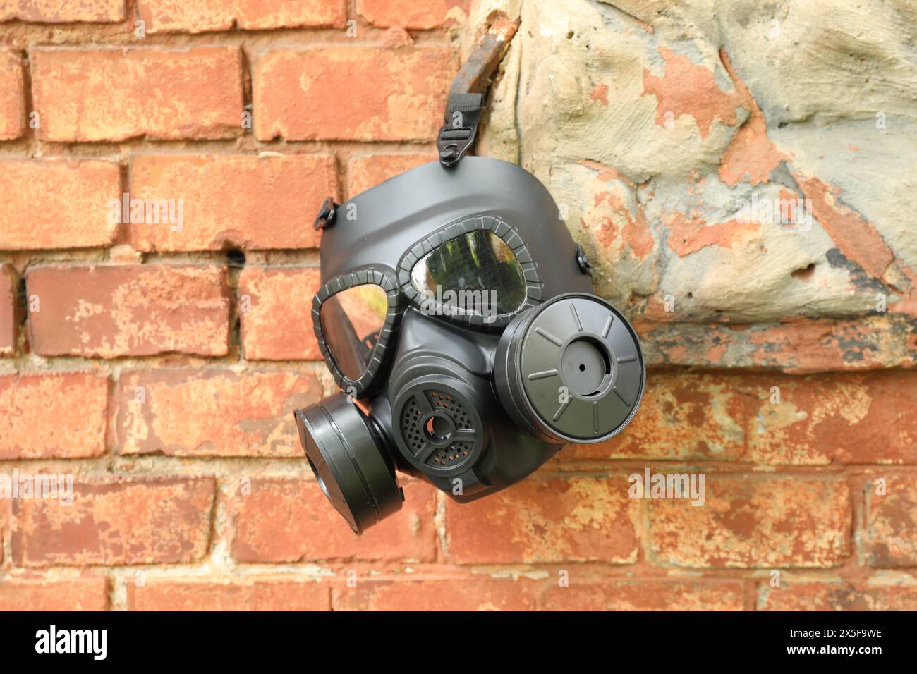 One gas mask hanging near brick wall on building Stock Photo - Alamy