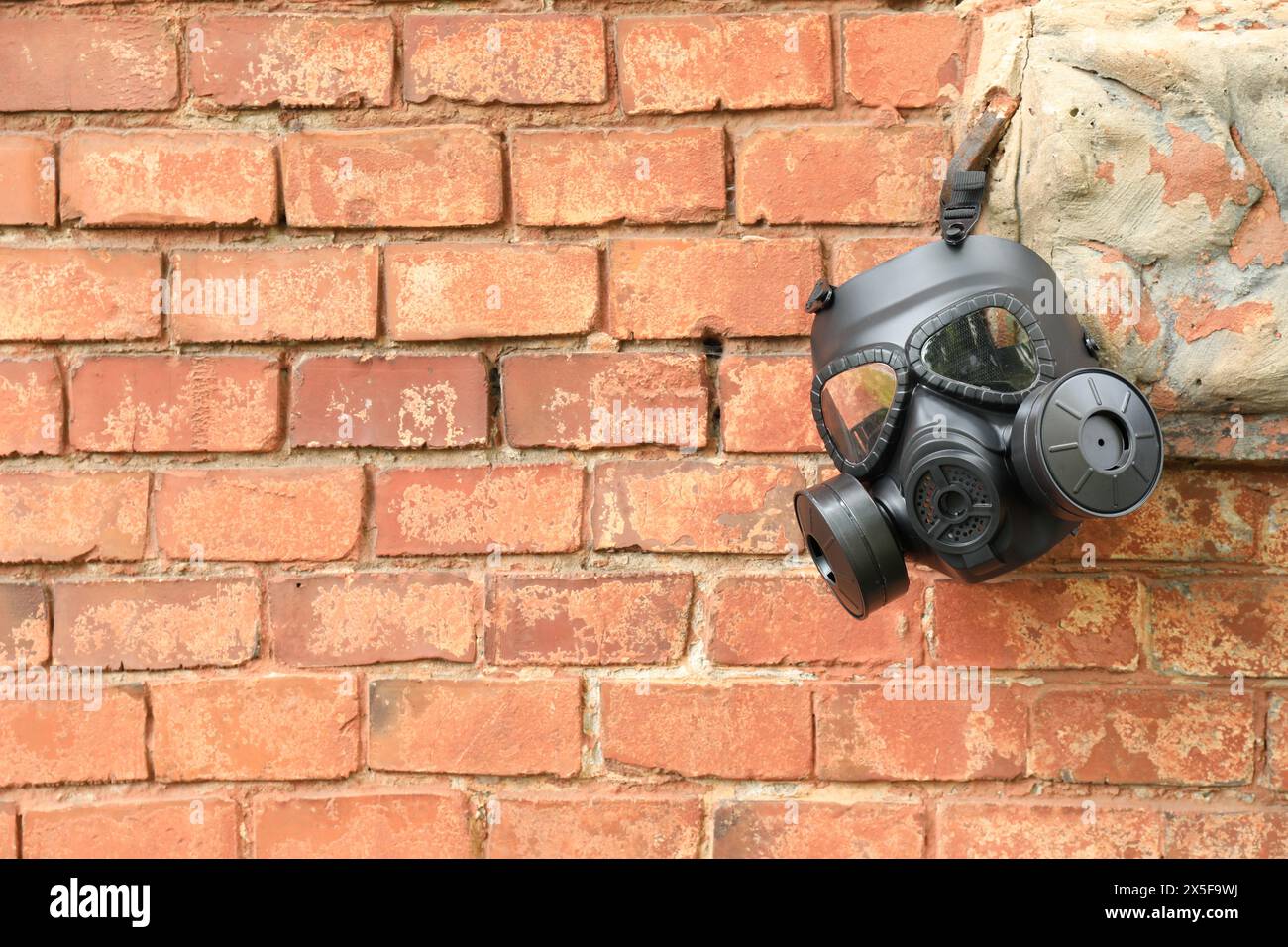 One gas mask hanging near brick wall on building. Space for text Stock ...
