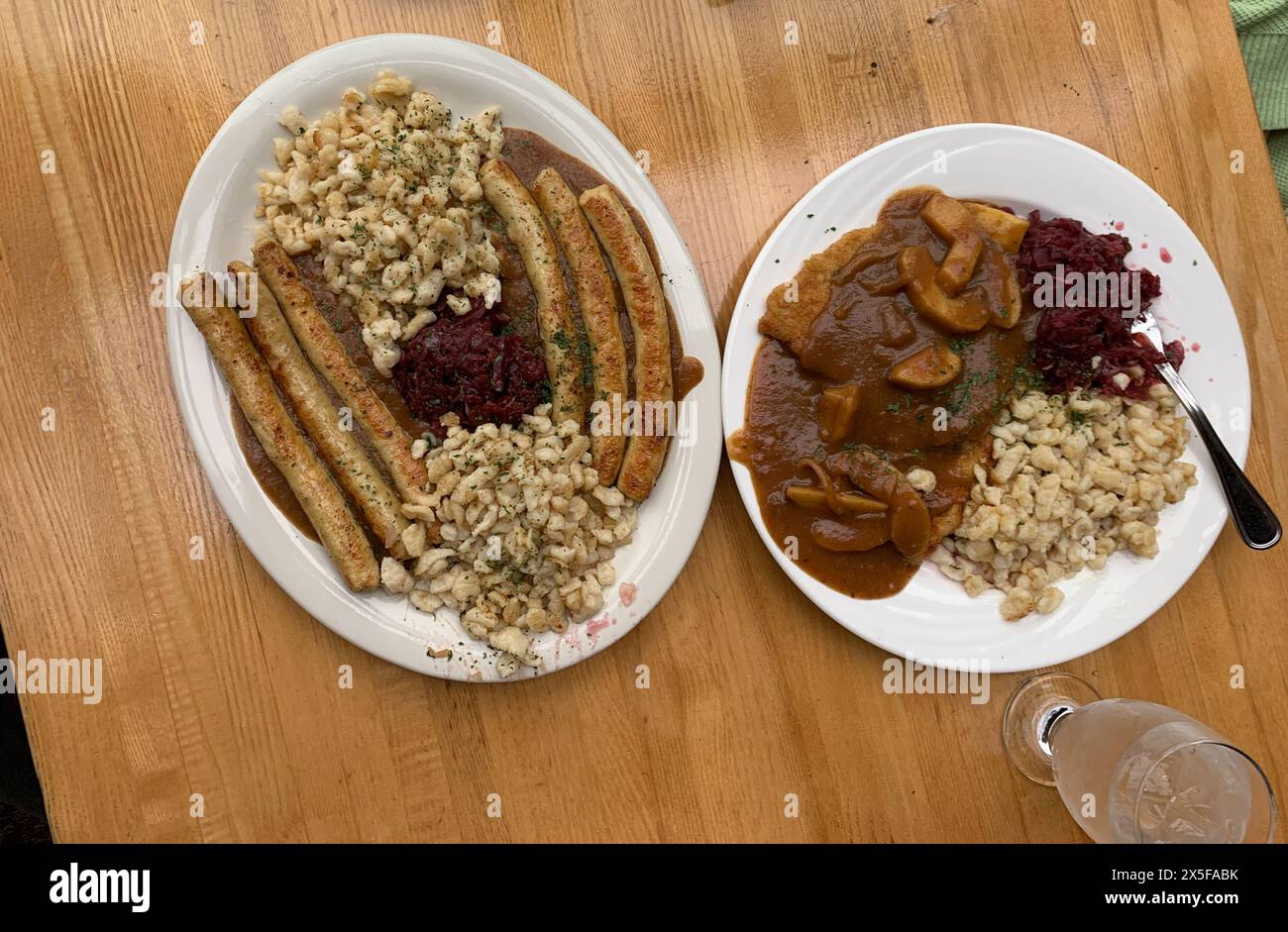 A plate of German food with chicken bratwurst sausages, potatoes, and ...