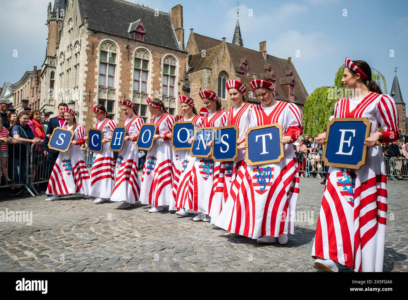 9th May 2024, Bruges, Belgium. Historical reenactors hold up one letter ...