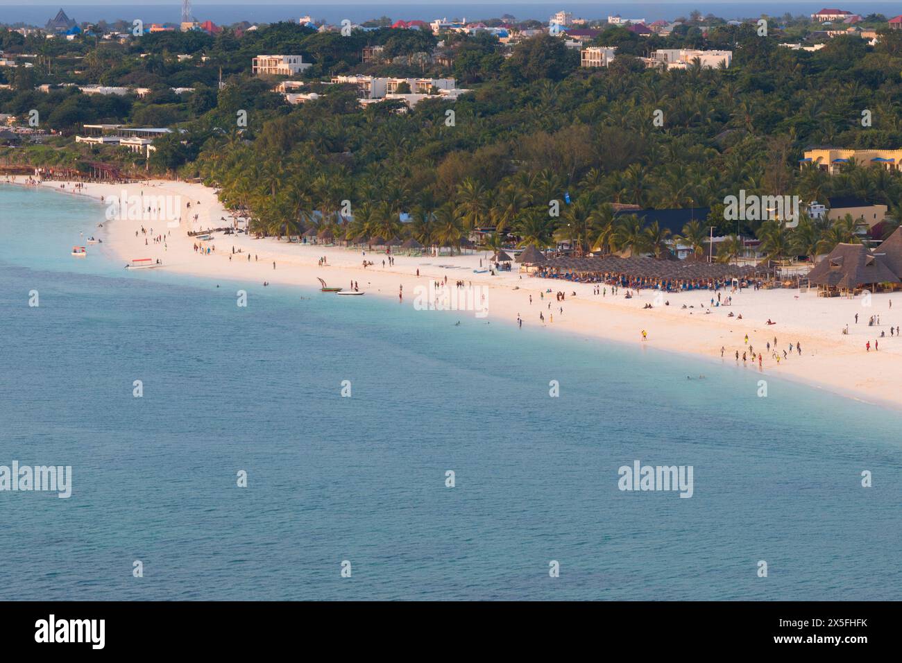Zanzibar beach with a lot of people, background luxury resort and palm ...