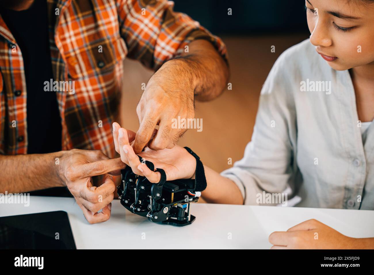 Teacher helps student build robotic arm in classroom design and ...