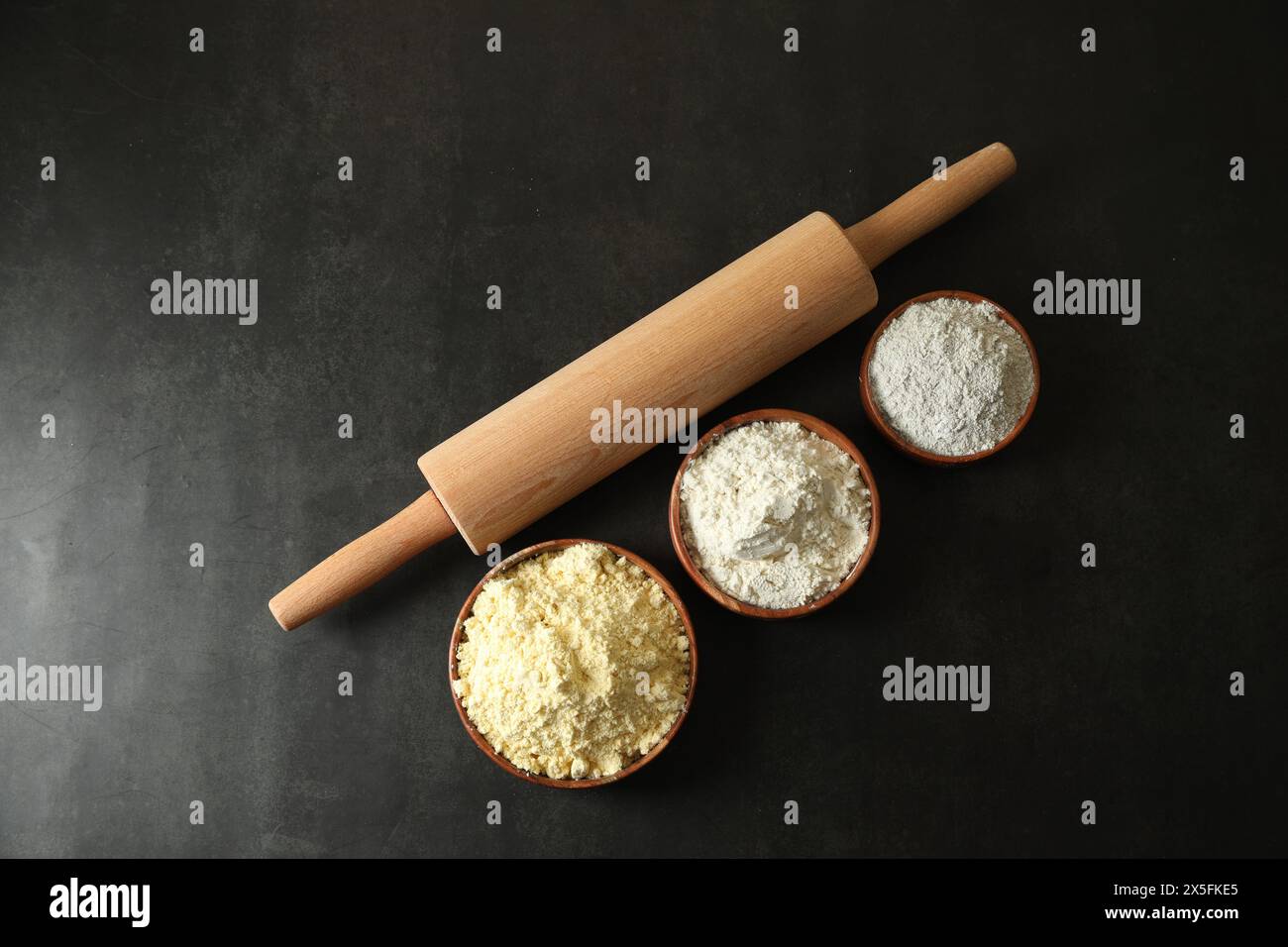 Rolling pin and different types of flour on black table, flat lay Stock ...