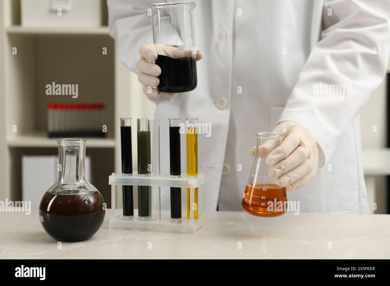 Laboratory worker holding beaker and flask with different types of ...