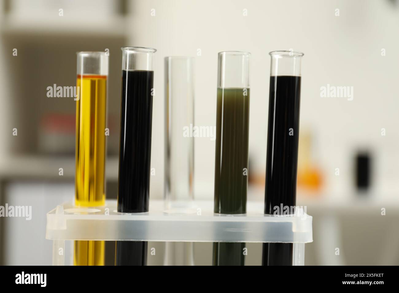 Test tubes with different types of crude oil against blurred background ...