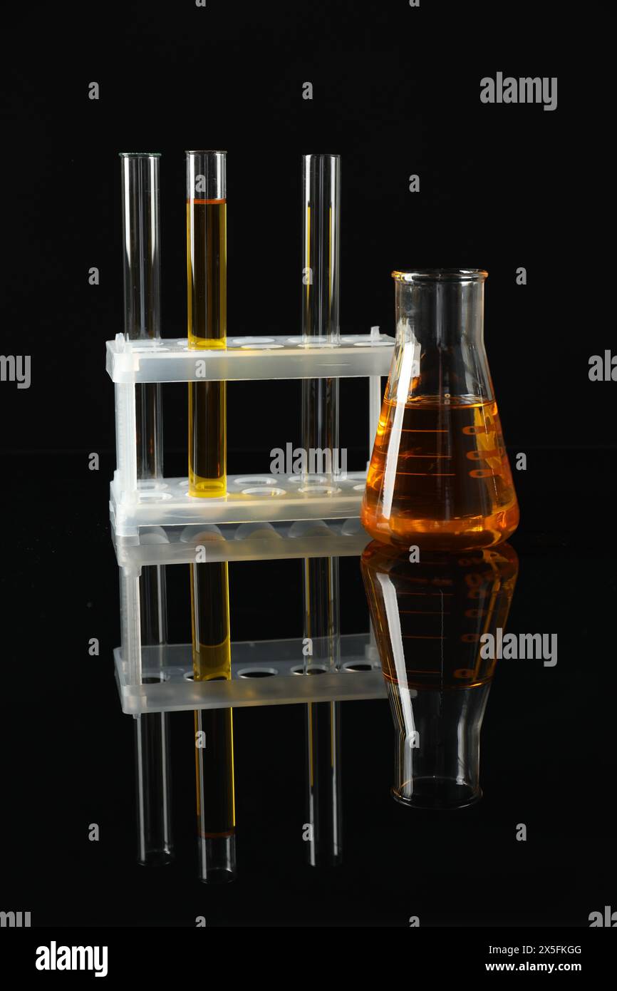 Laboratory glassware with different types of oil on black background ...
