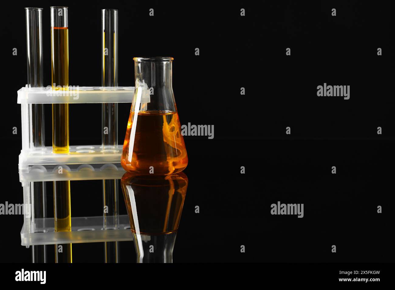 Laboratory glassware with different types of oil on black background ...