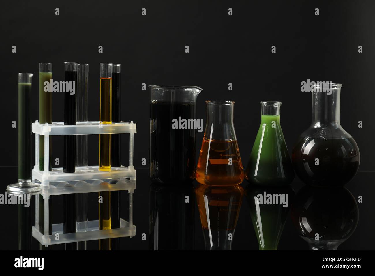 Laboratory glassware with different types of oil on black background ...