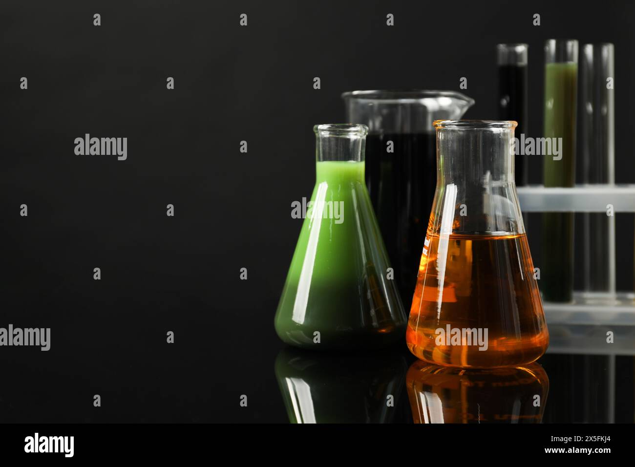 Laboratory glassware with different types of oil on black background ...