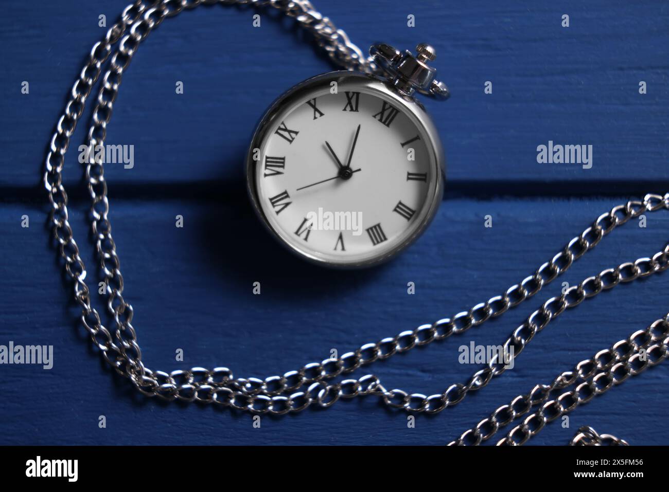 Silver pocket clock with chain on blue wooden table, top view Stock ...