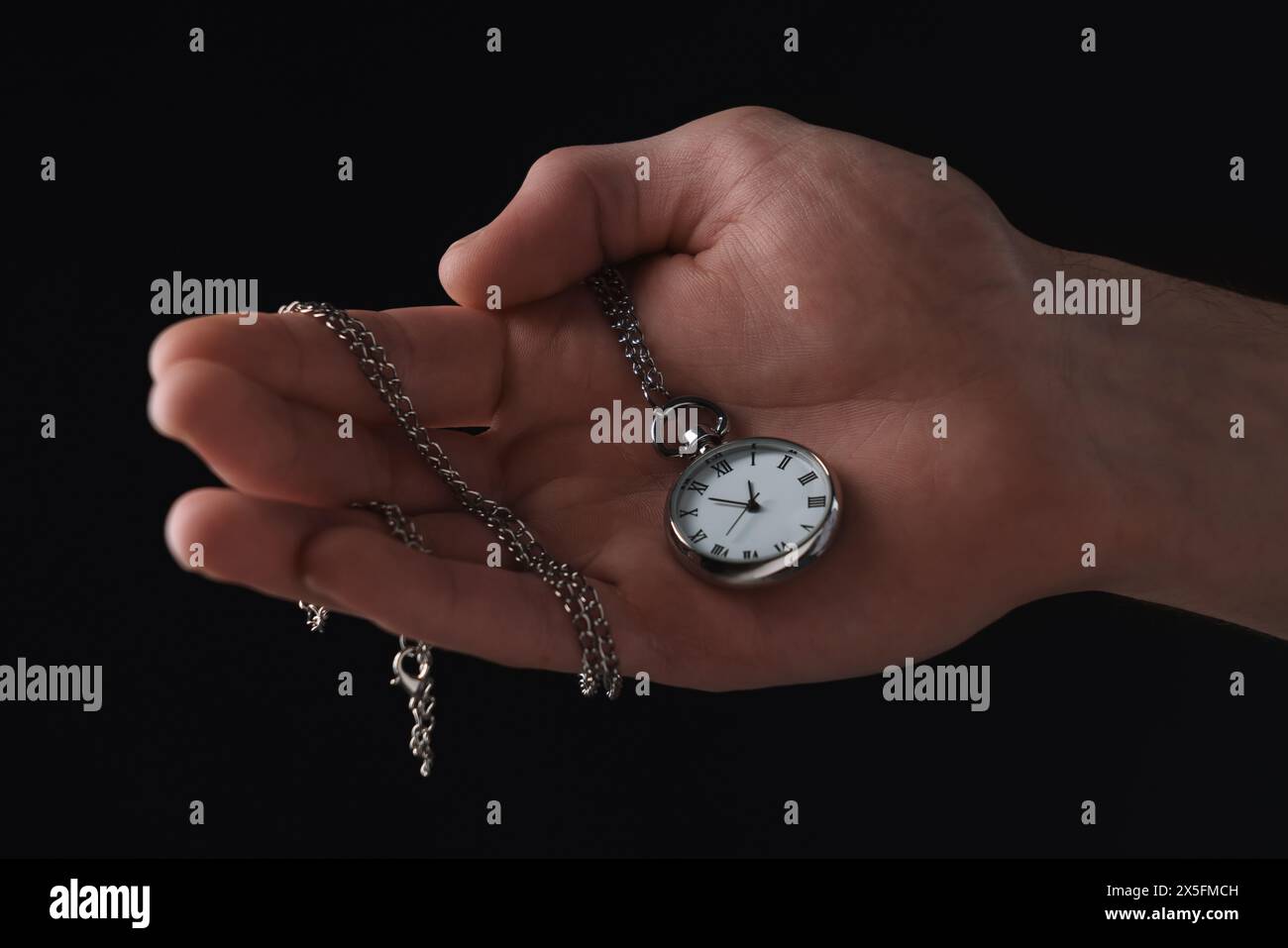 Man holding chain with elegant pocket watch on black background ...