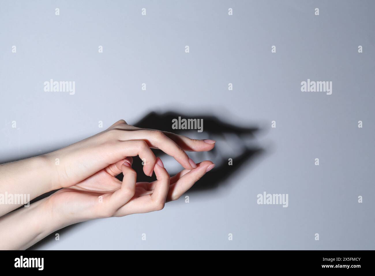 Shadow puppet. Woman making hand gesture like crocodile on grey ...