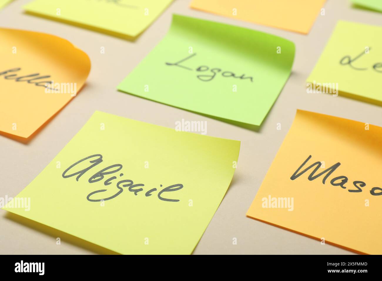 Paper stickers with different names on beige background, closeup ...