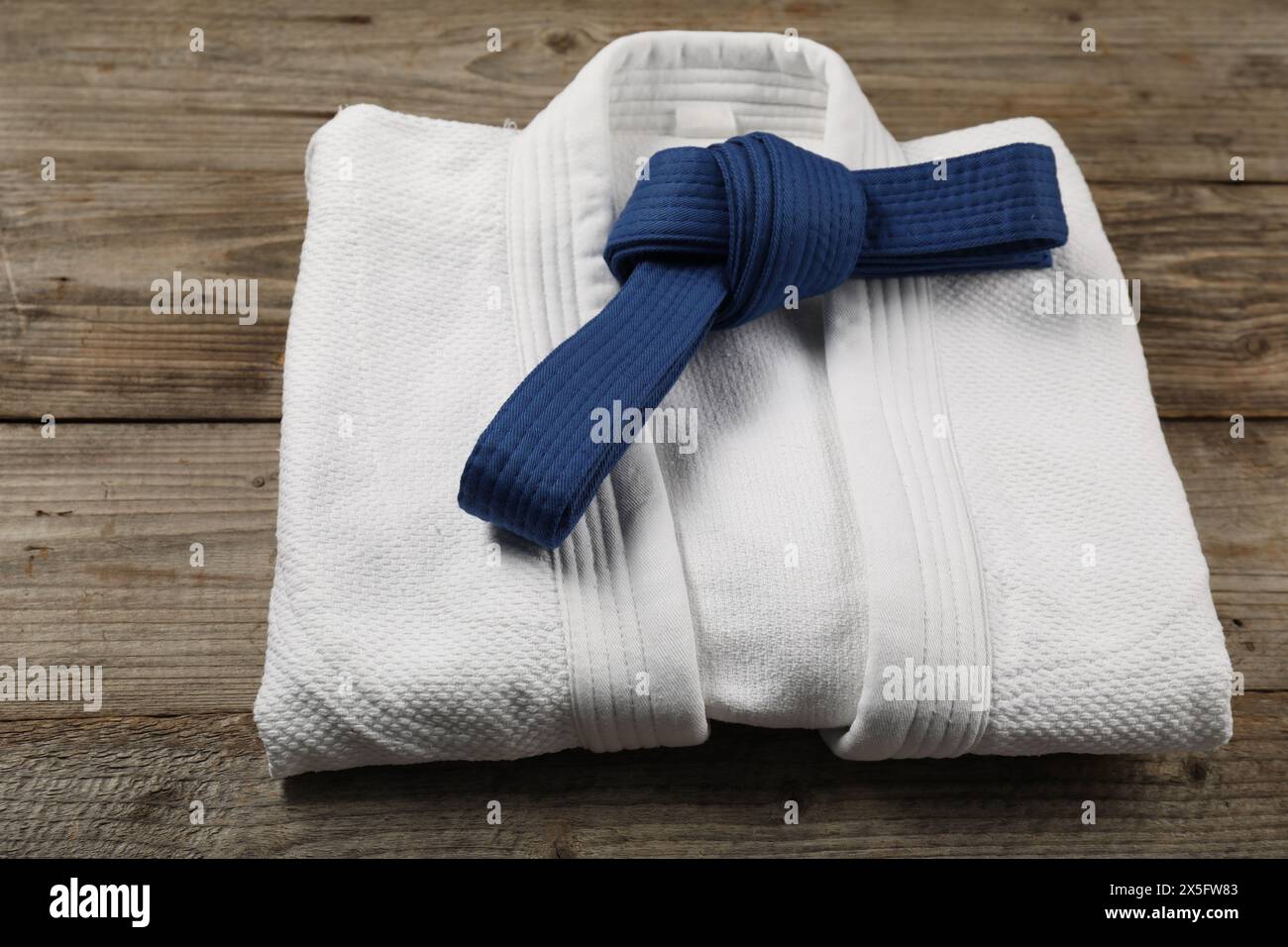 Blue karate belt and white kimono on wooden background Stock Photo - Alamy