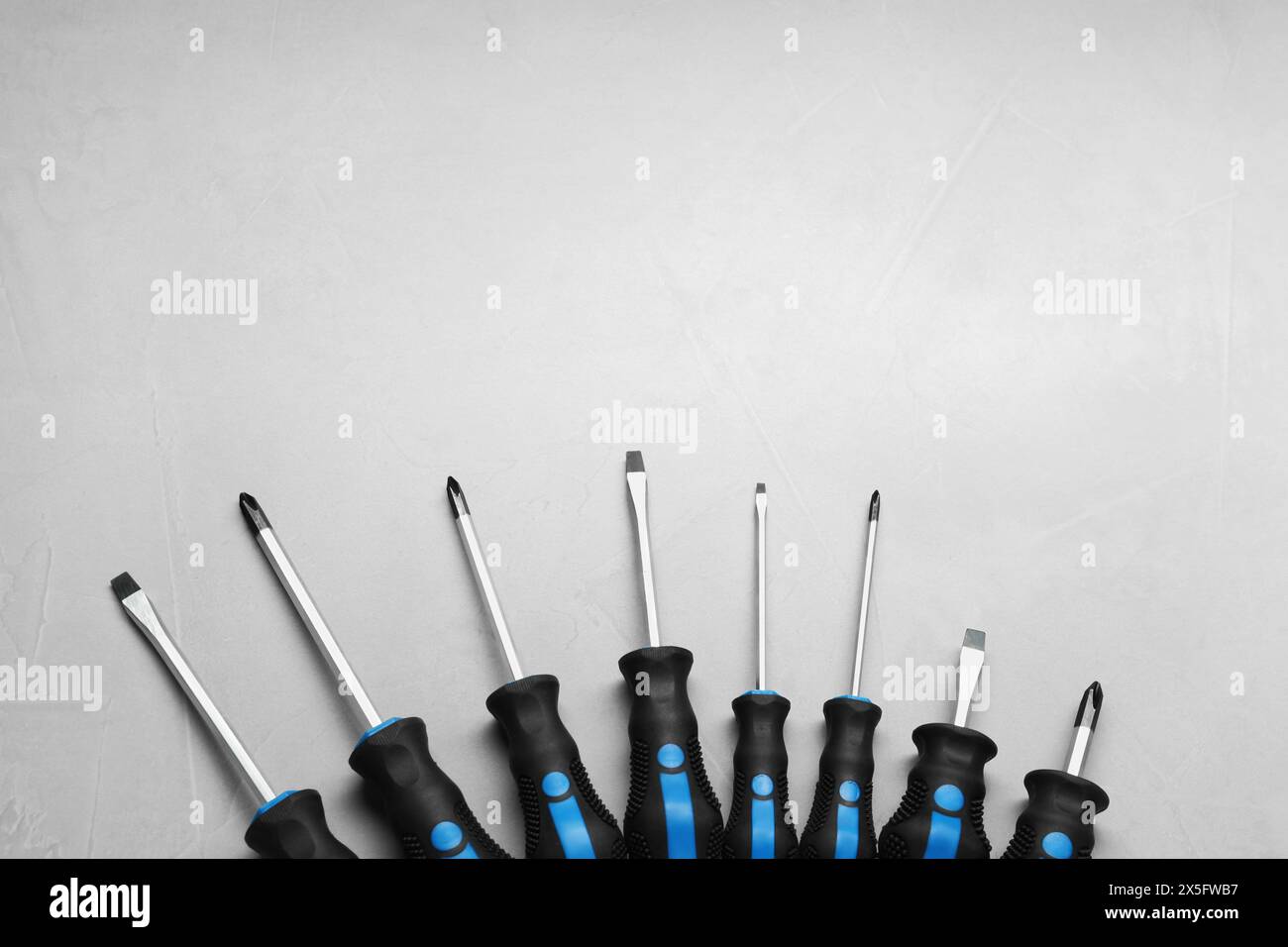 Set of screwdrivers on light grey background, flat lay. Space for text ...