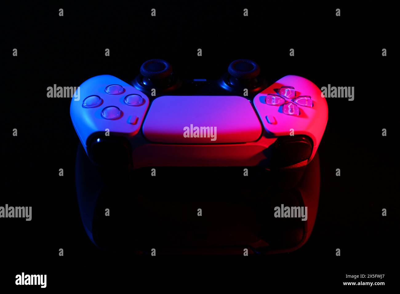Wireless game controller on black mirror surface in neon lights Stock ...