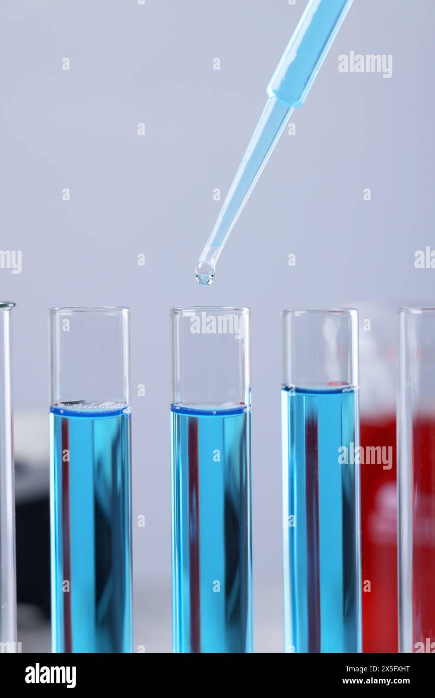 Dripping liquid from pipette into test tube on blurred background ...