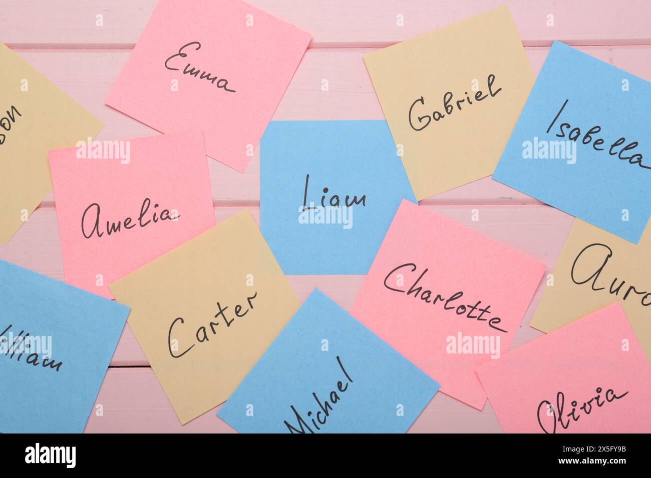 Paper stickers with different names on pink wooden background, flat lay ...