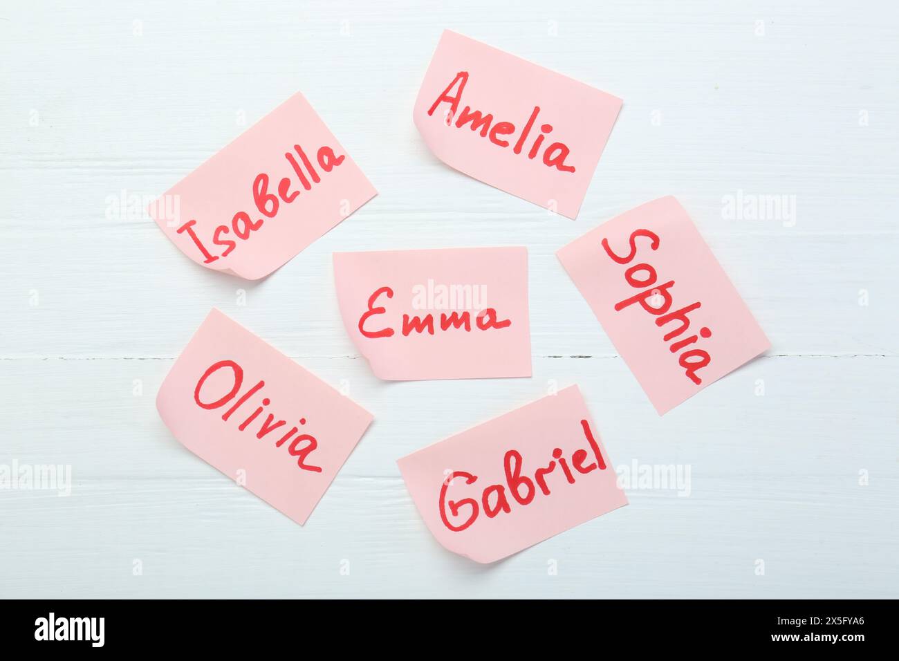Paper stickers with different names on white wooden background, flat ...