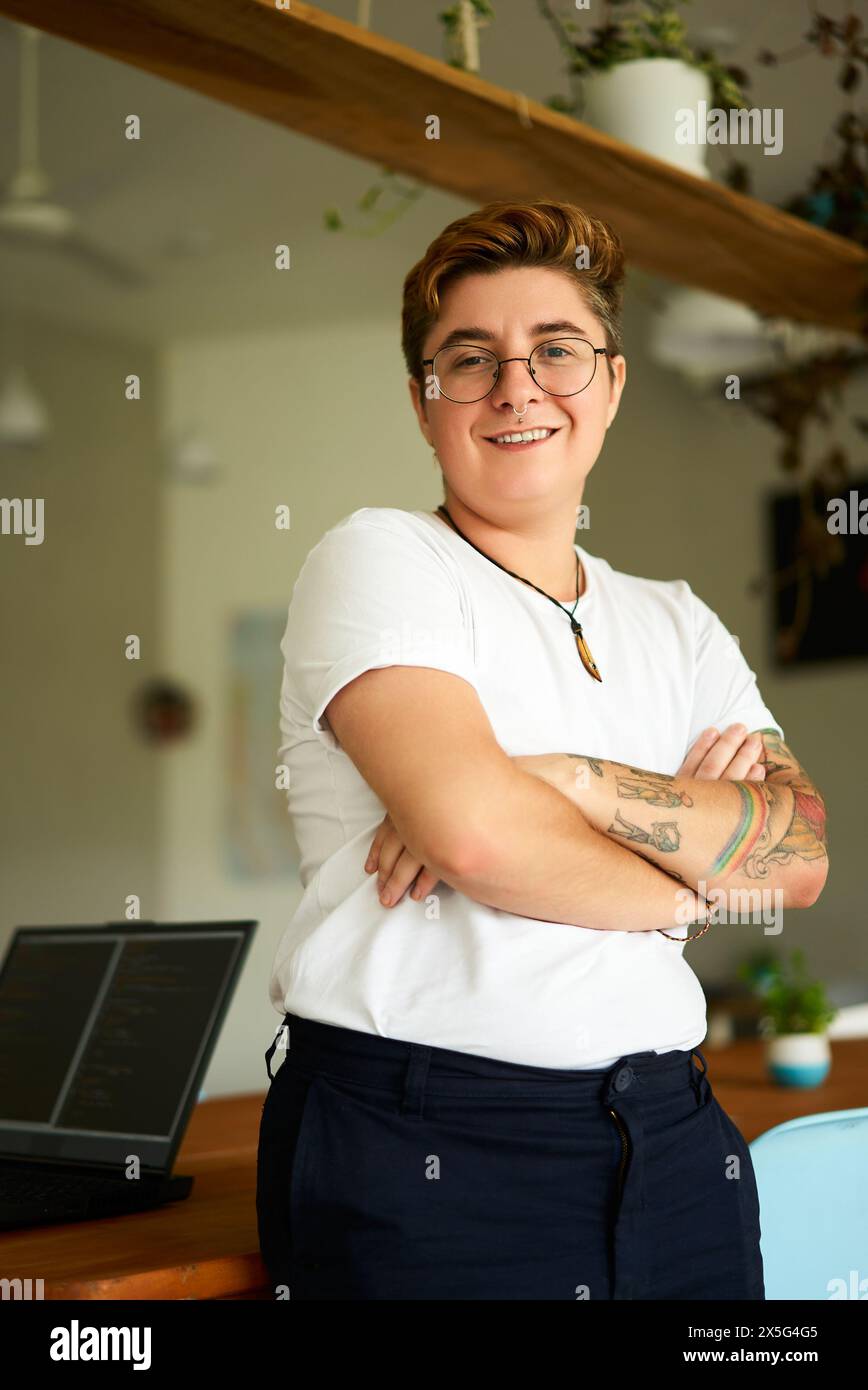 Confident transgender pro in office attire stands with arms folded ...