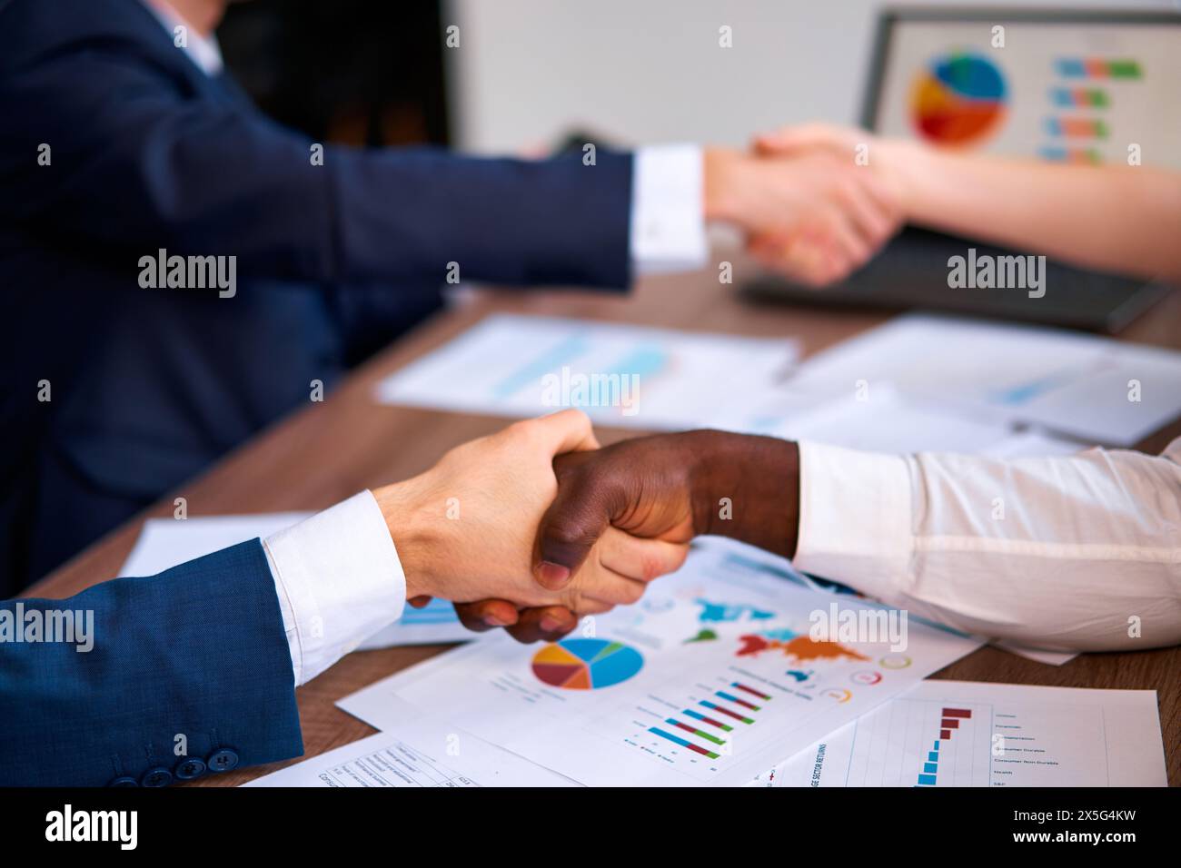 Multiracial professionals handshake closing at office meeting. Charts ...