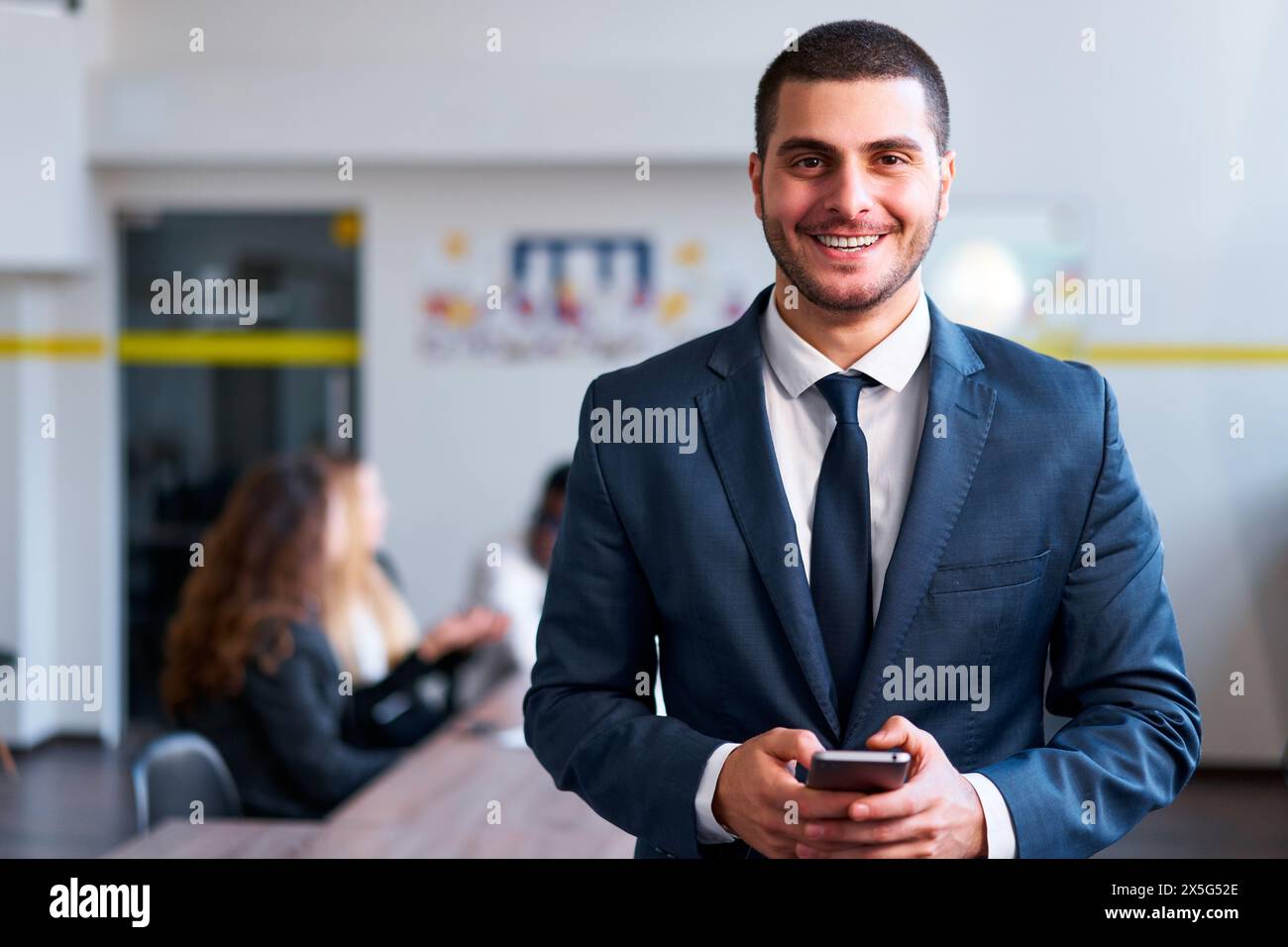 Smartly dressed eastern businessman smiles, holding smartphone in ...