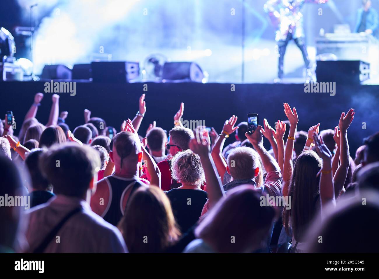 Energetic audience enjoys night concert, raising hands, recording live ...