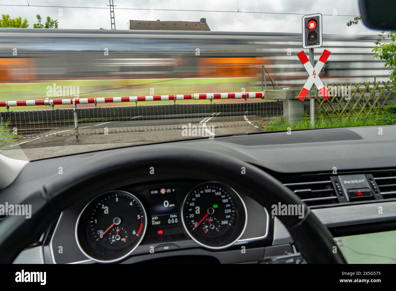 Car waiting at a level crossing, closed barriers, red warning light ...