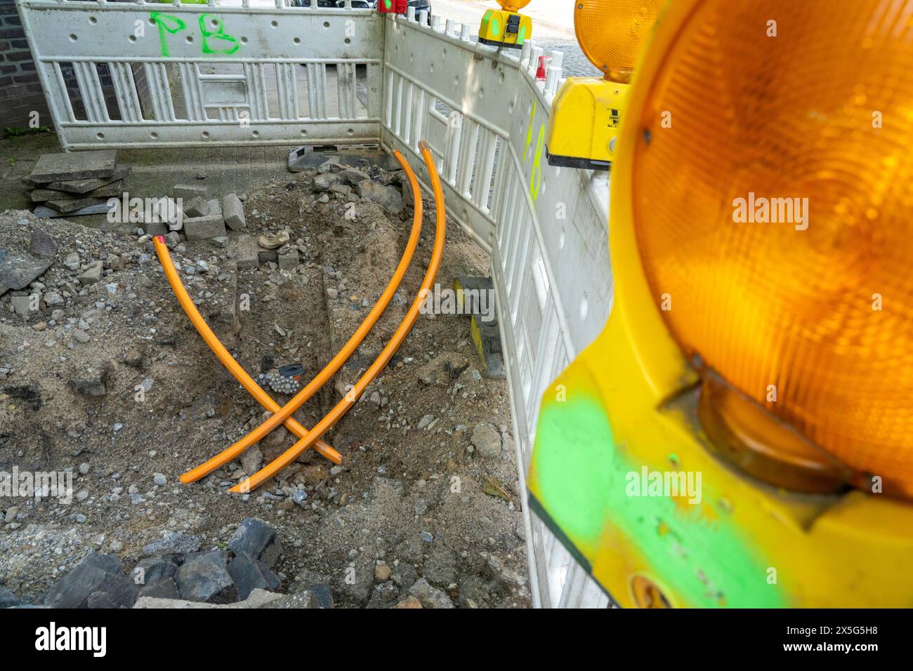 Laying of fiber optic cables, empty conduits are laid under a sidewalk ...