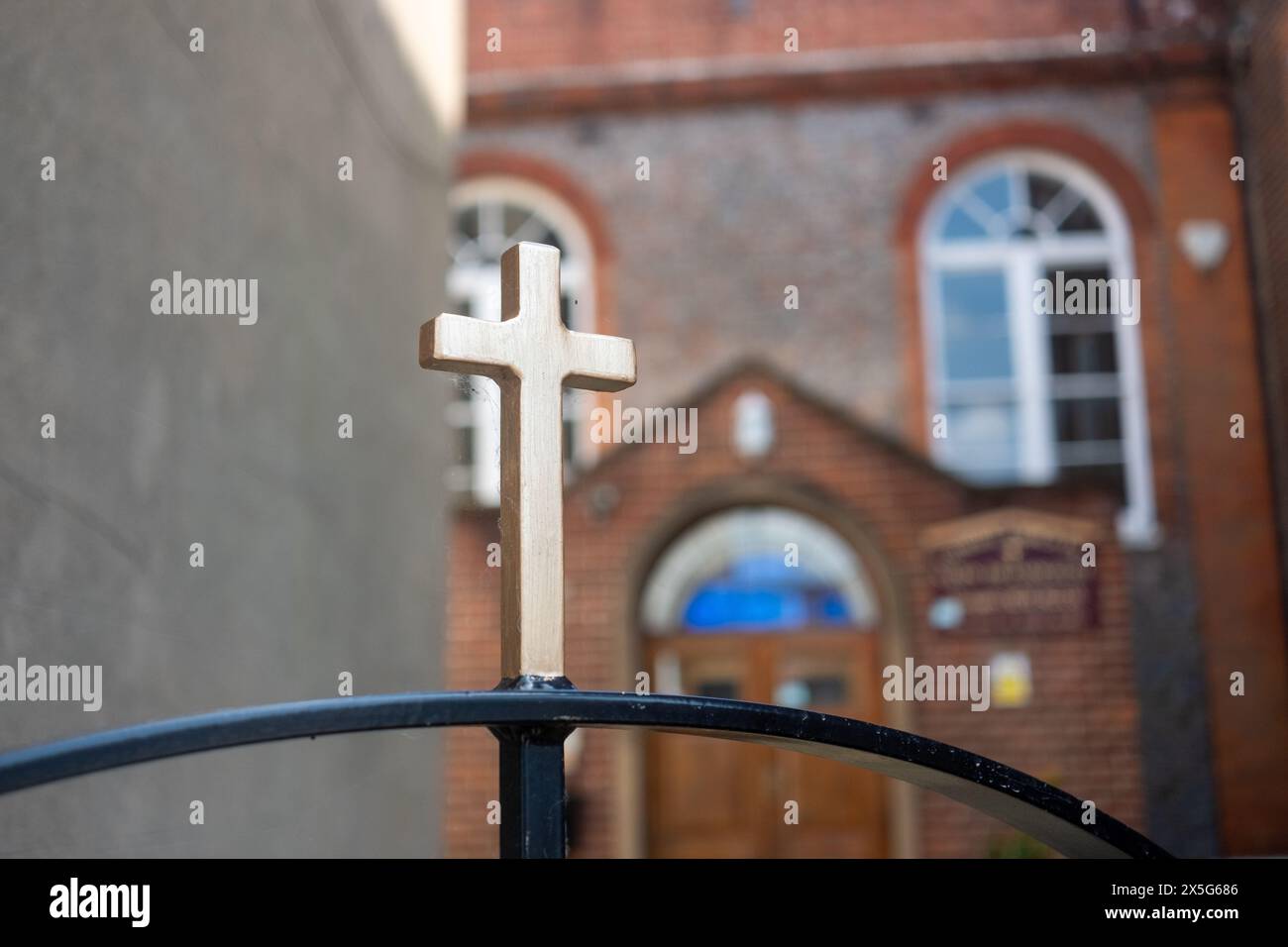 Cross in focus with The Catholic Church of St John the Evangelist in ...