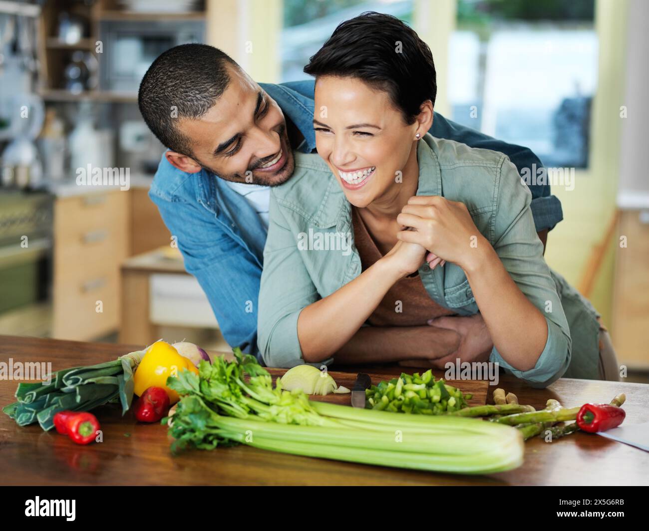 Cooking, smile and couple embrace at kitchen counter for preparation ...