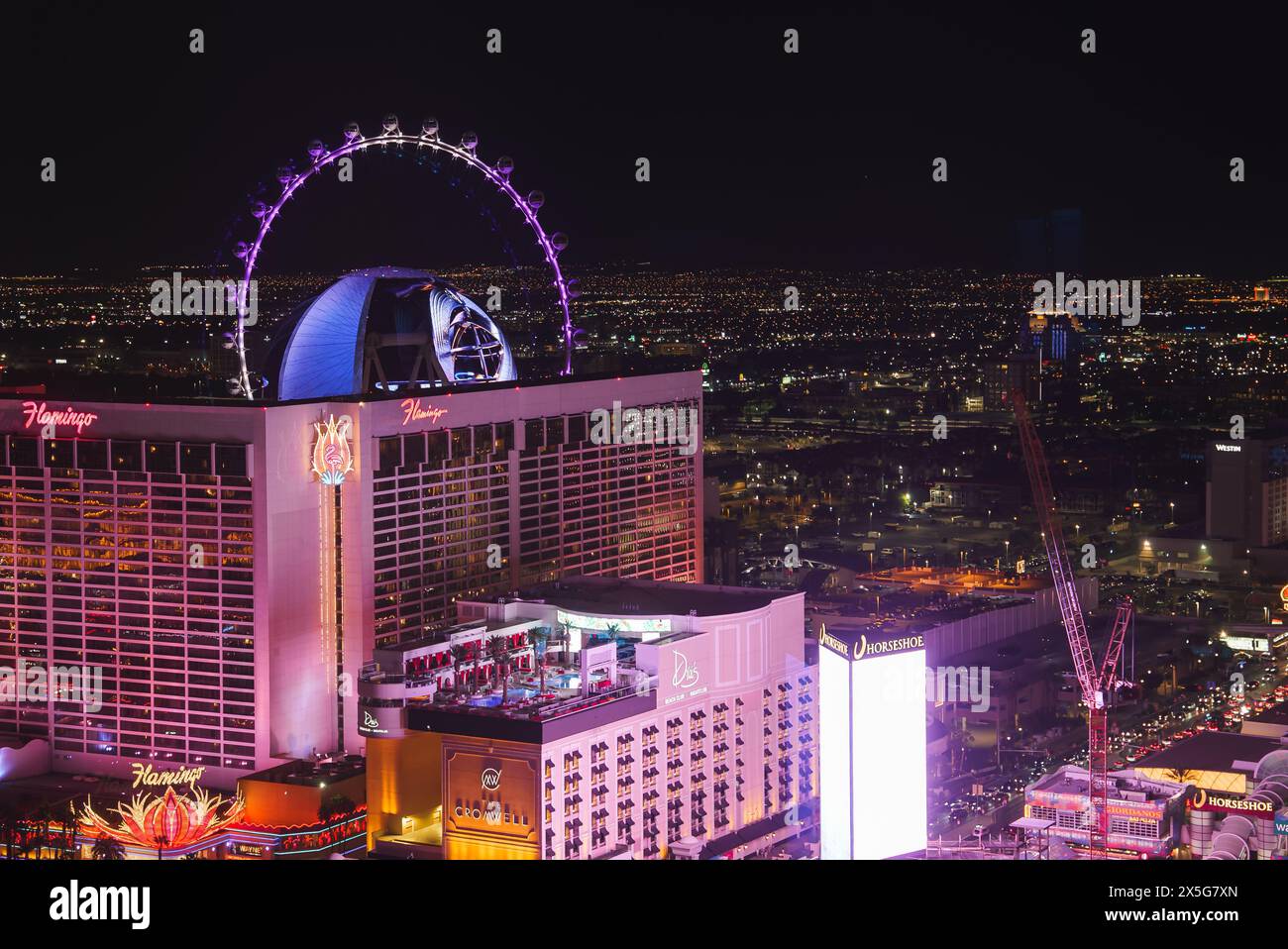 Vibrant night view of Las Vegas Strip w or High Roller Ferris wheel and neon Flamingo Hotel ...