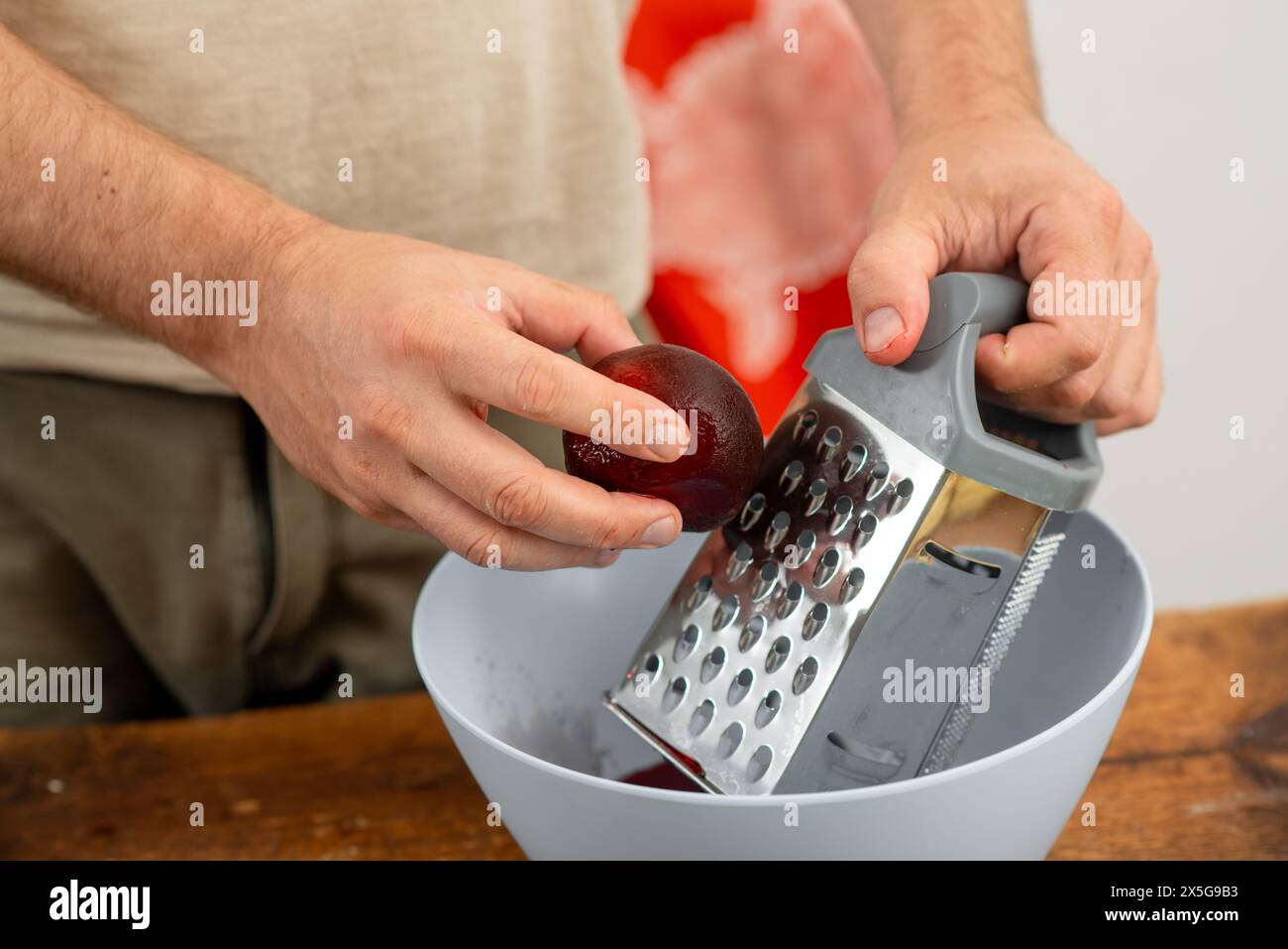 Making beet salad: hands with red beet juice using a metal grater Stock ...