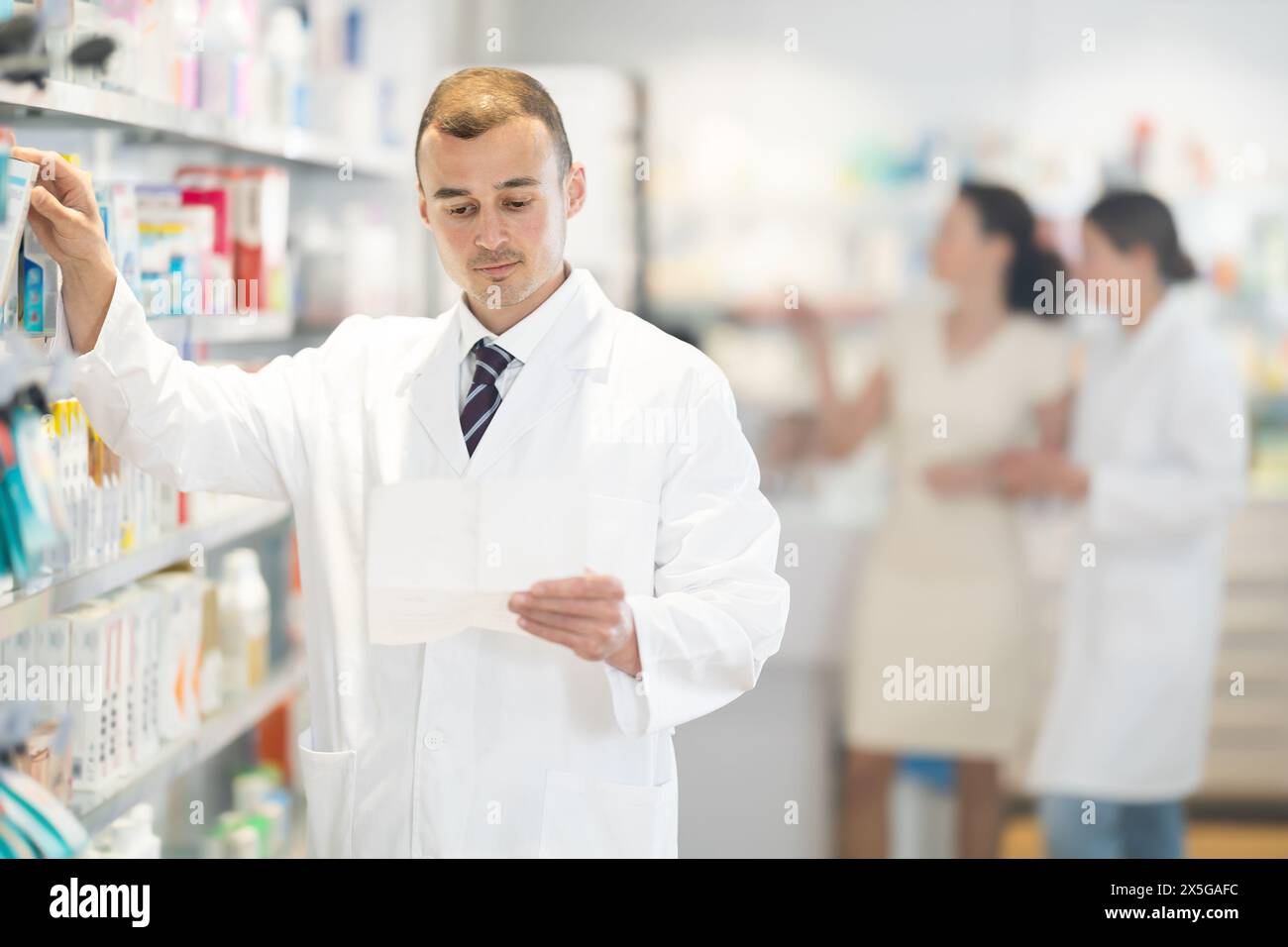 Positive male pharmacist in medical uniform posing while working in ...