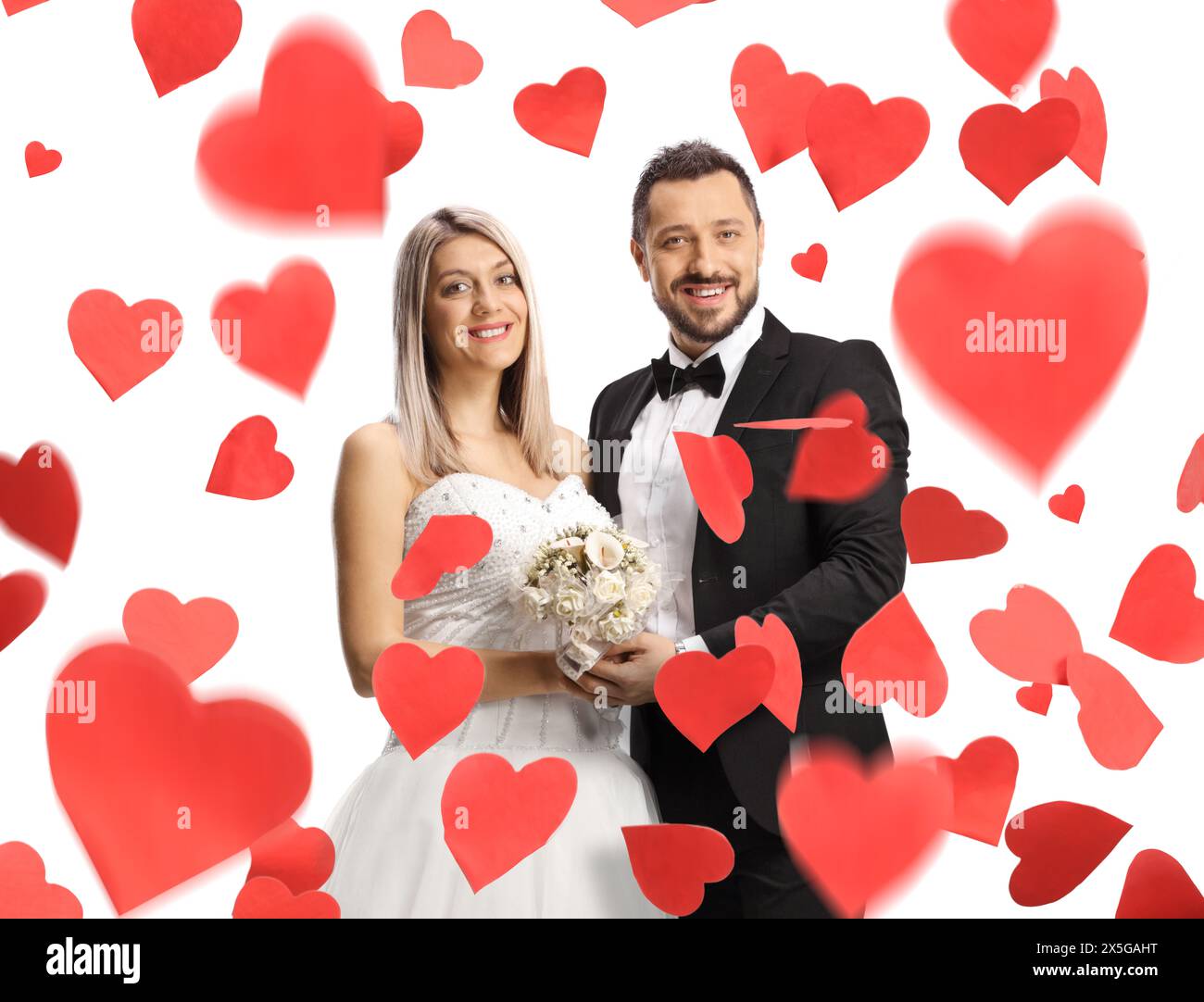 Happily married bride and groom standing under red hearts isolated on ...