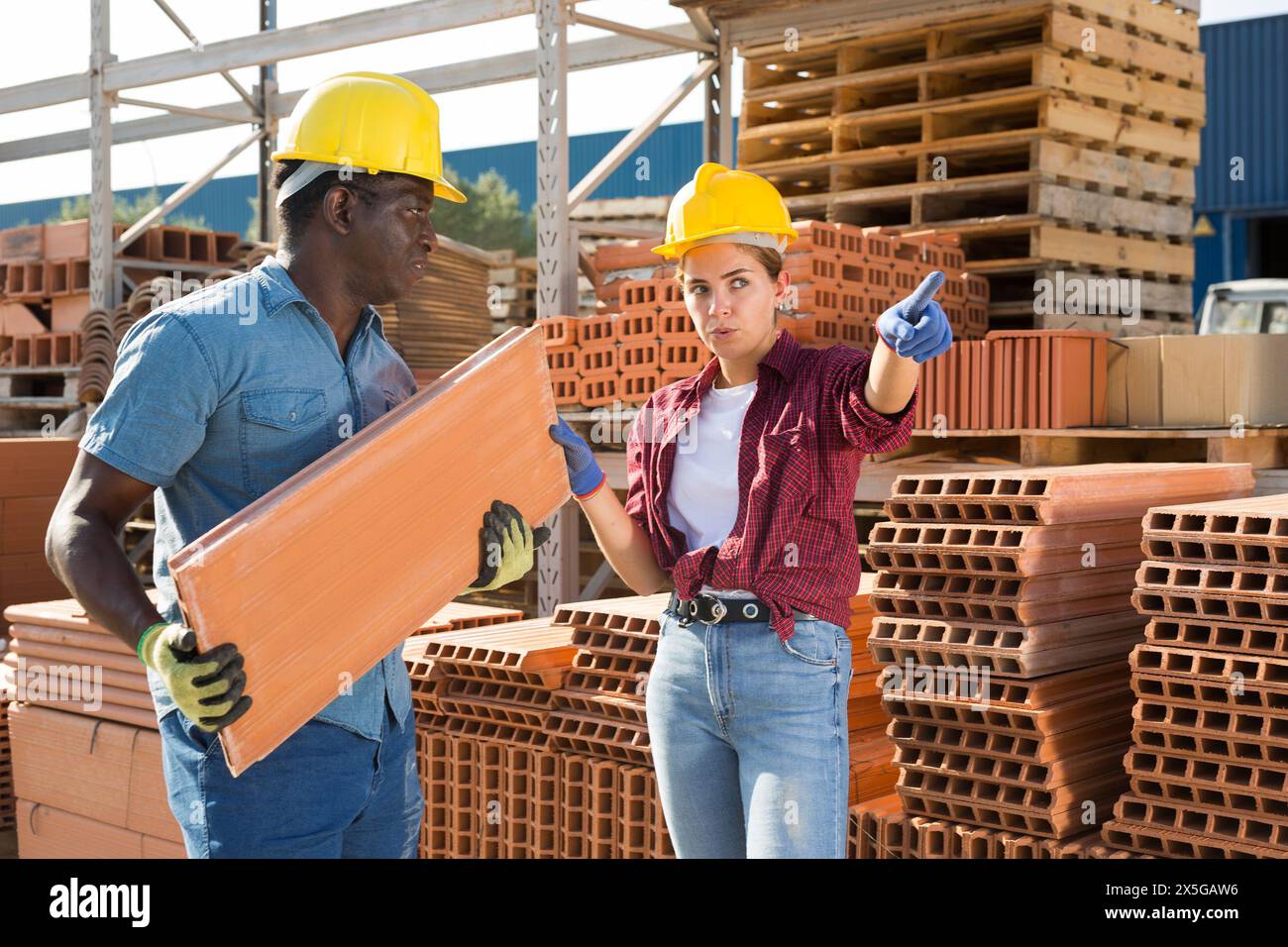 Female manager giving instructions to worker where to carry brick ...