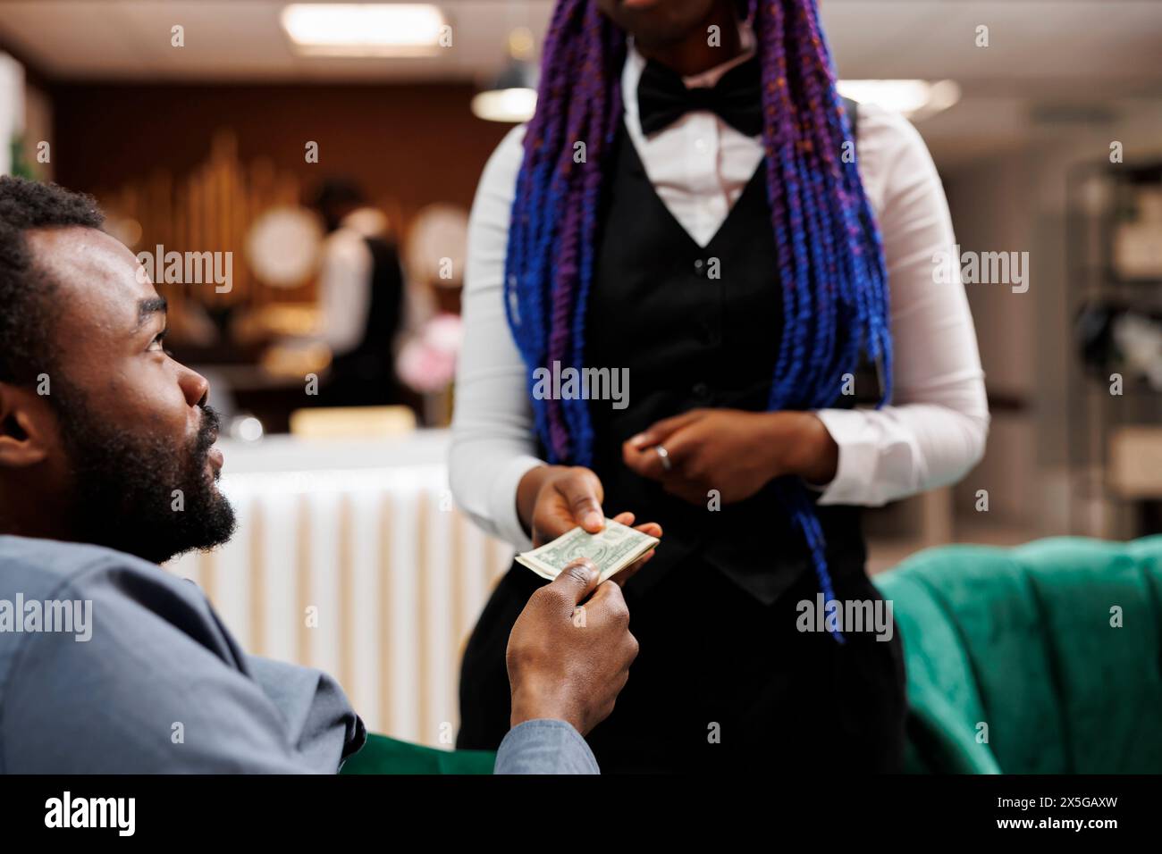 Young African American man hotel guest giving cash to waitress while ...