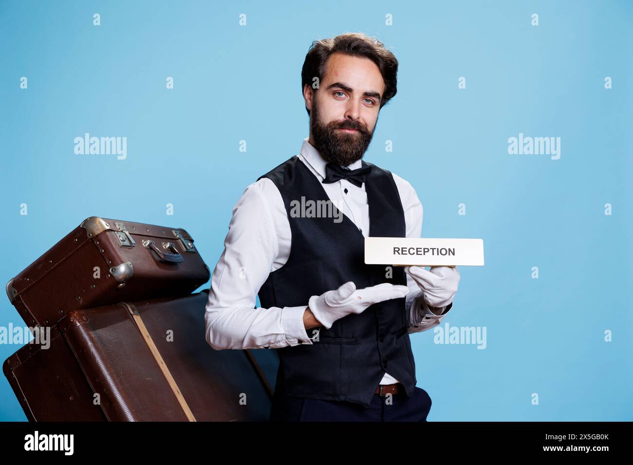 Doorman poses with sign of reception that guides persons to the hotel ...