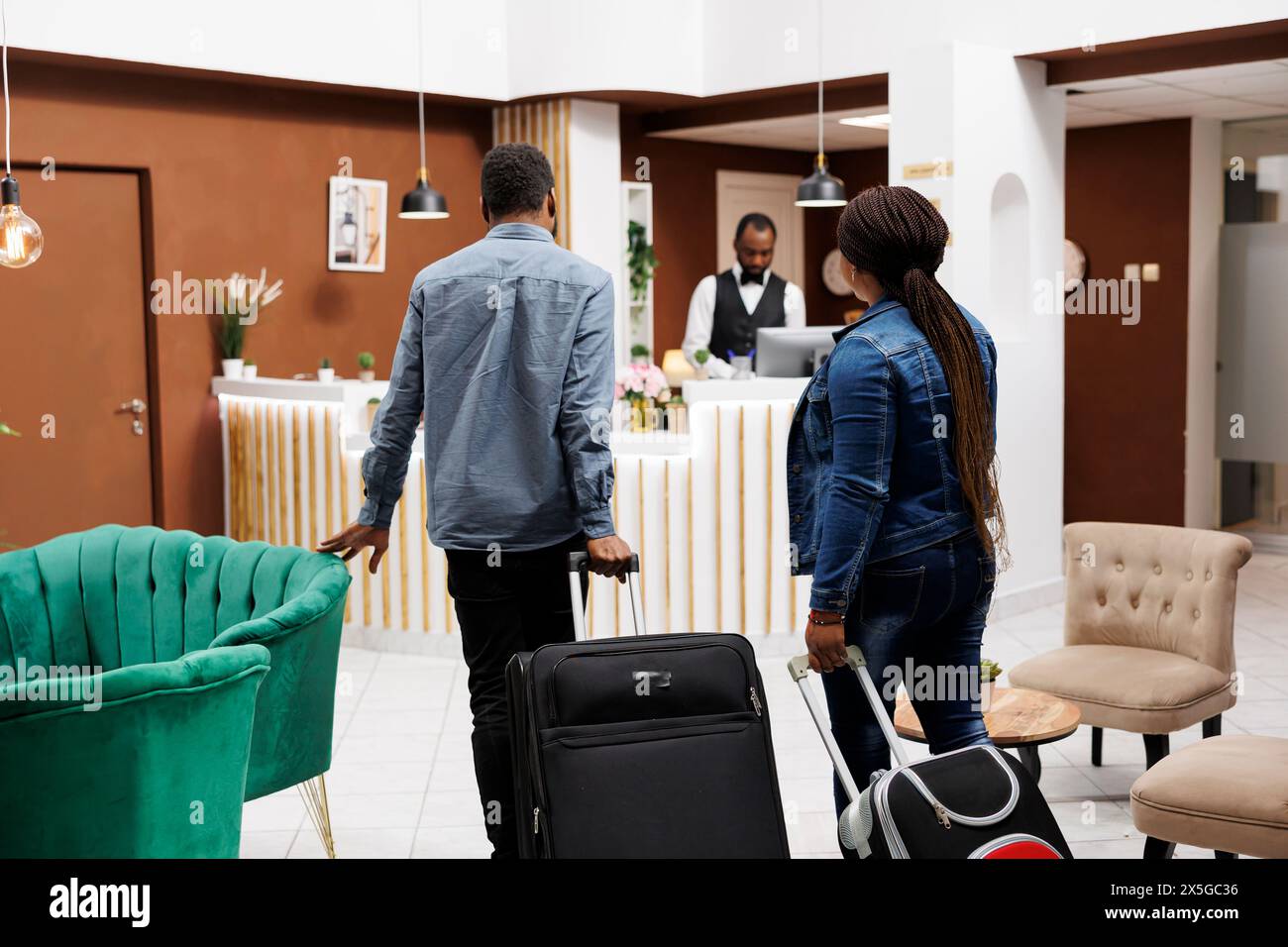 Rear view of young African American family couple arriving to resort ...