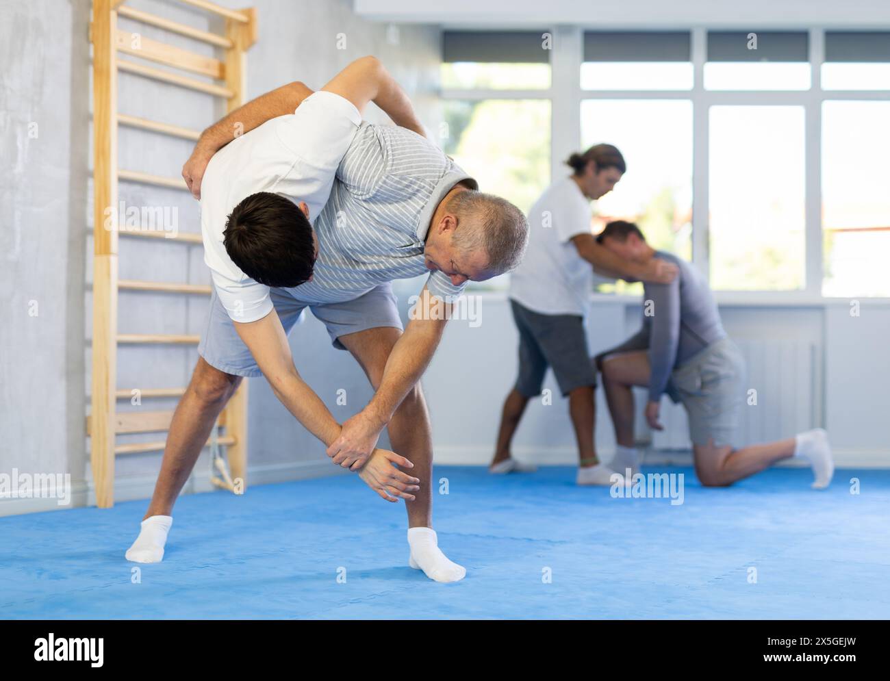 Two men of different ages in judo sparring - older man throws young guy ...