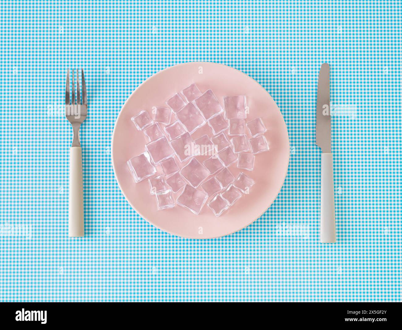 Creative layout made with pink plate, ice cubes, knife and fork on ...