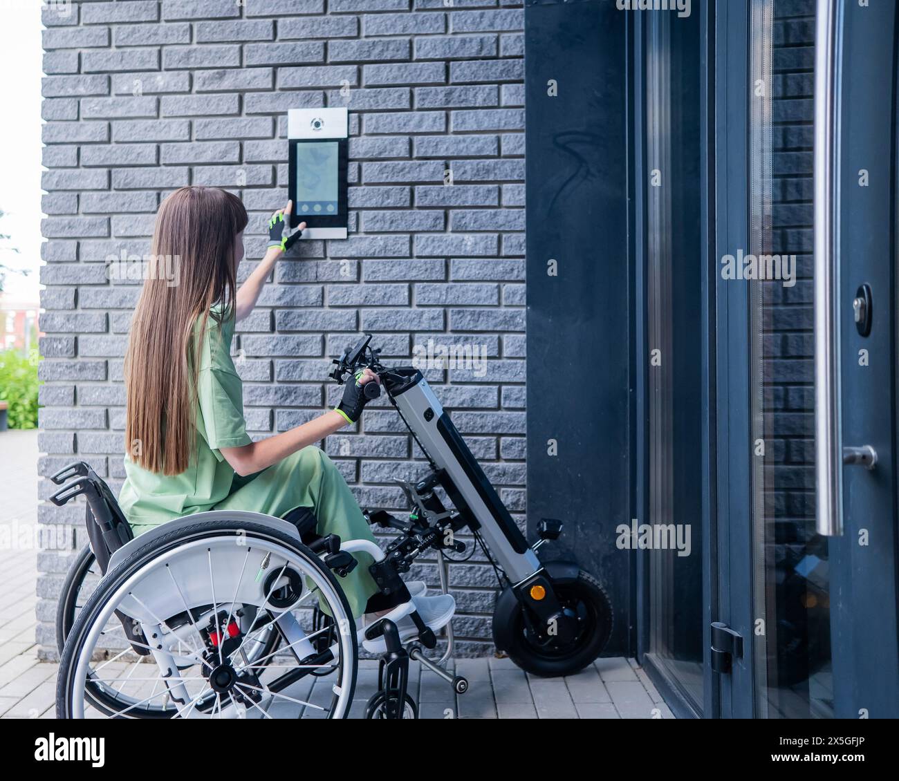 A woman in a wheelchair with an assistive device for manual control ...