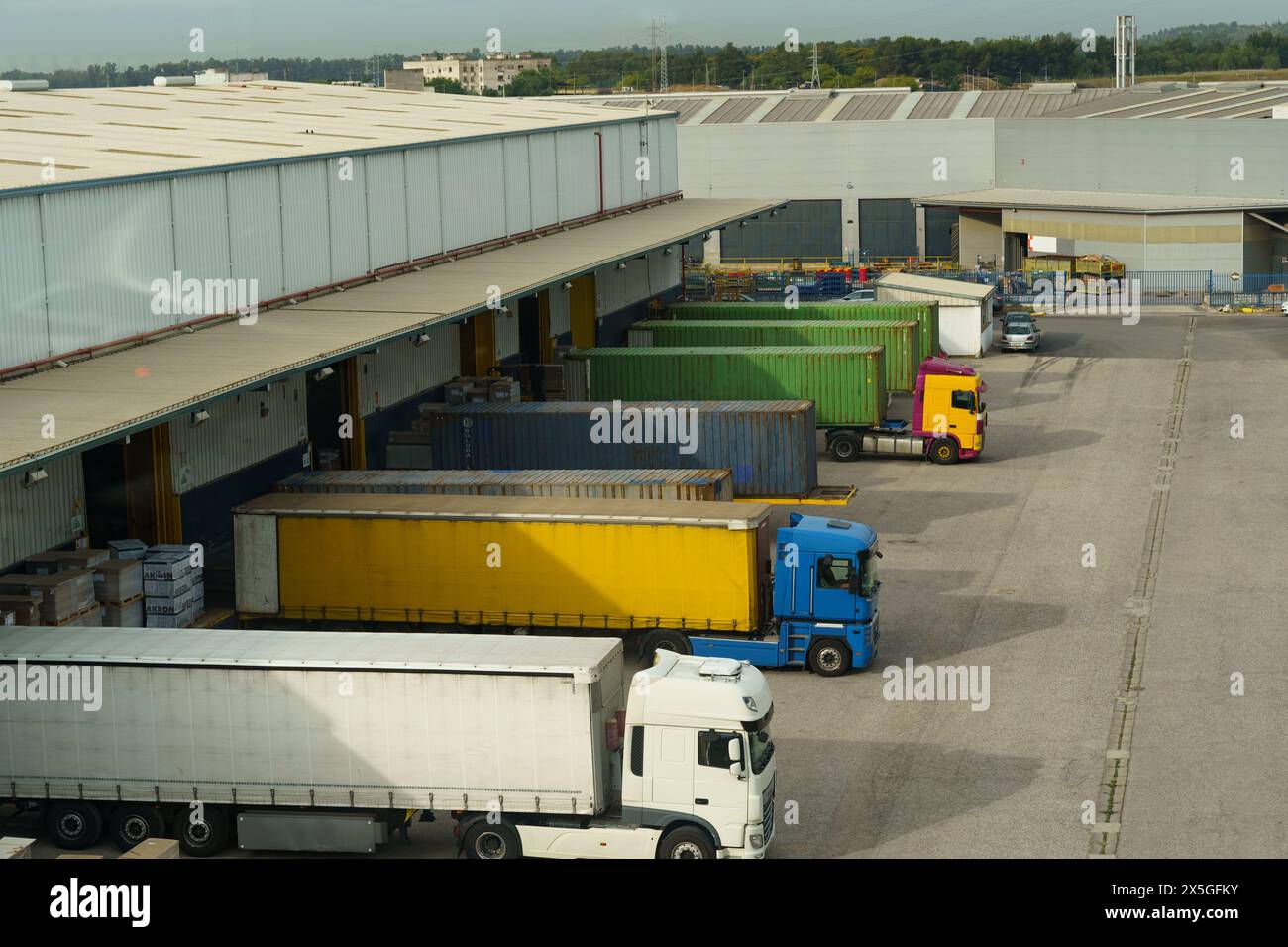 Trucks docked at a cargo bay with colorful freight containers ...
