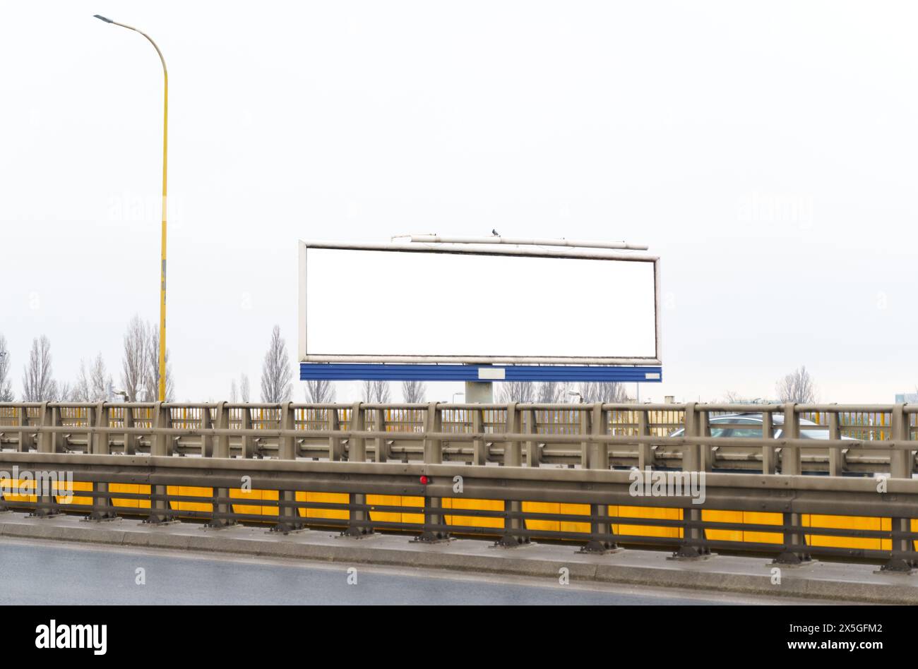 A wide white billboard with a mockup advertisement stands prominently ...