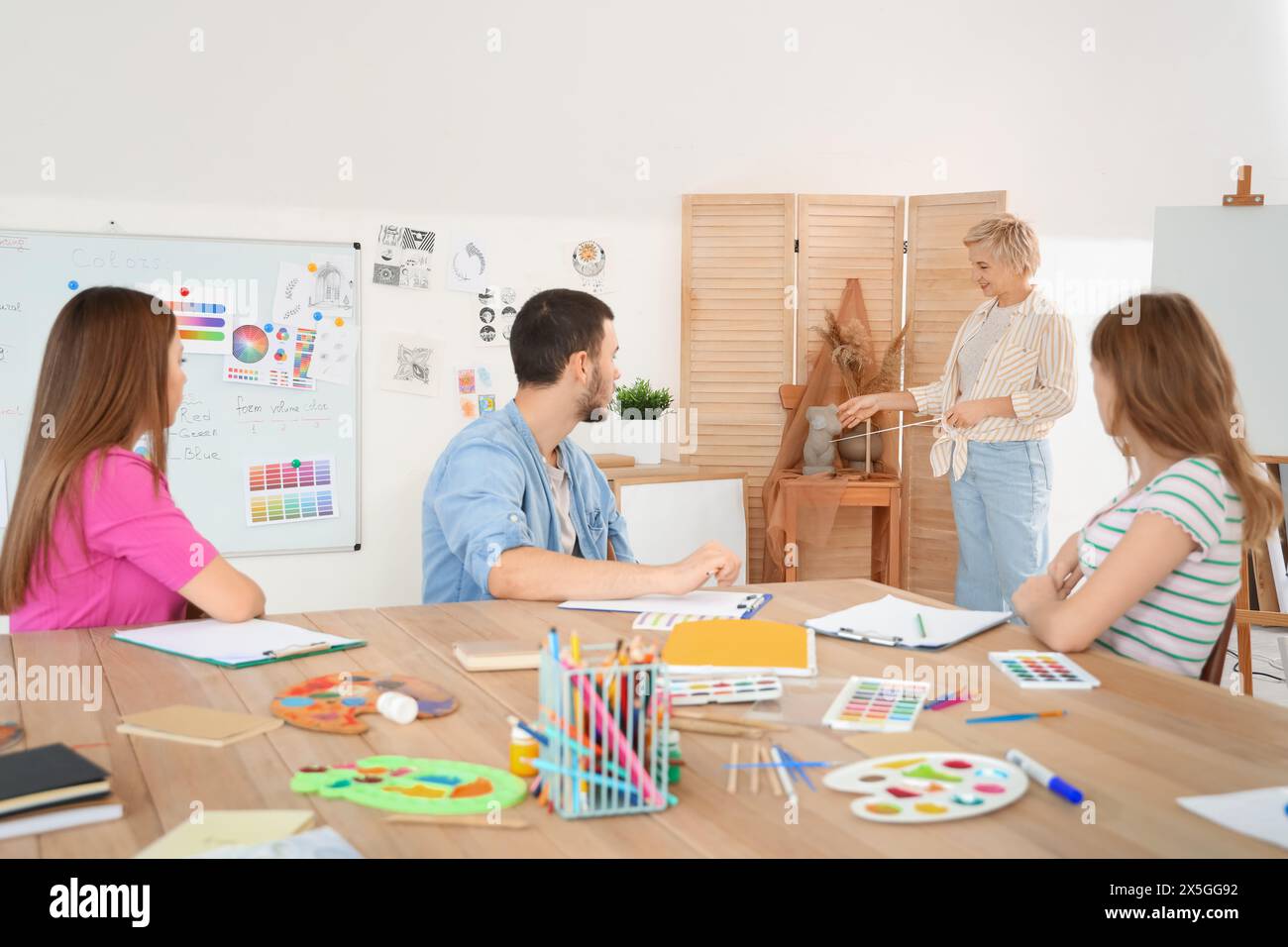 Female art teacher giving lesson to students at school Stock Photo - Alamy
