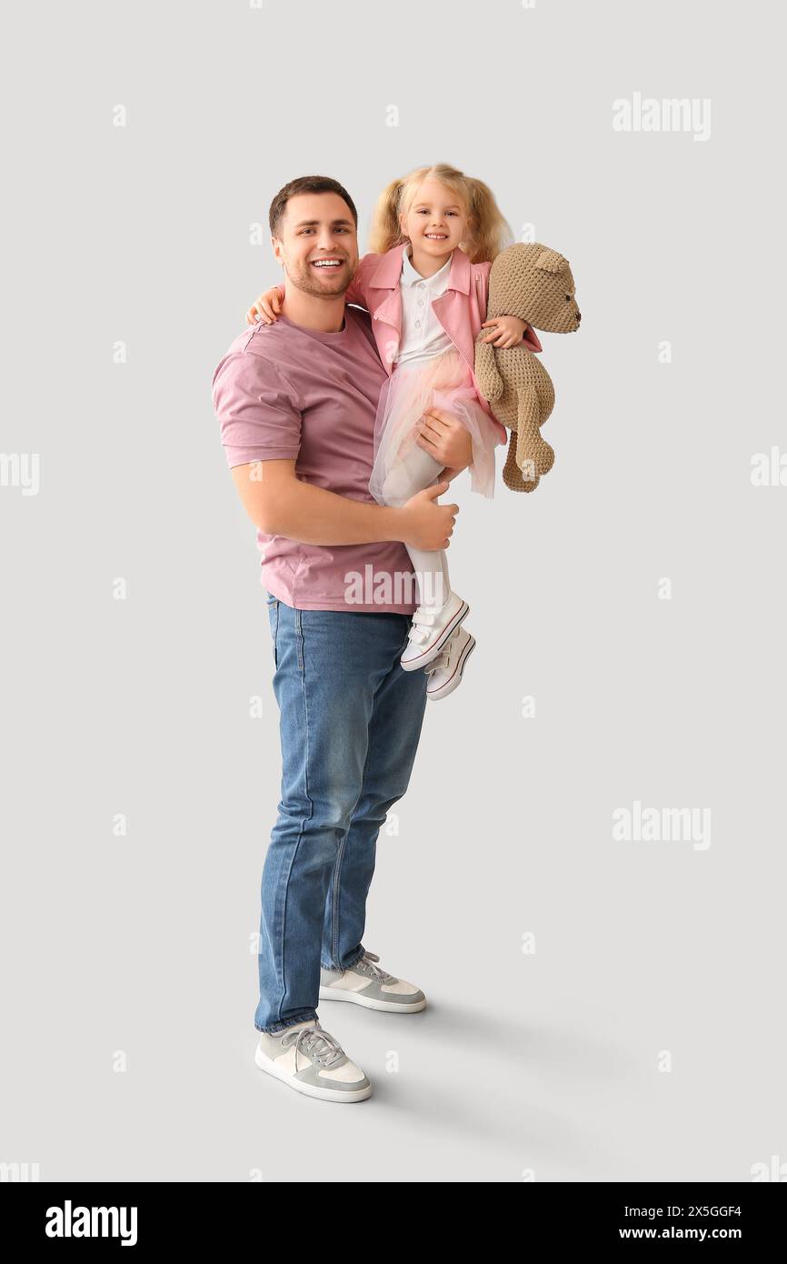Happy father and his cute little daughter with teddy bear on grey background Stock Photo - Alamy