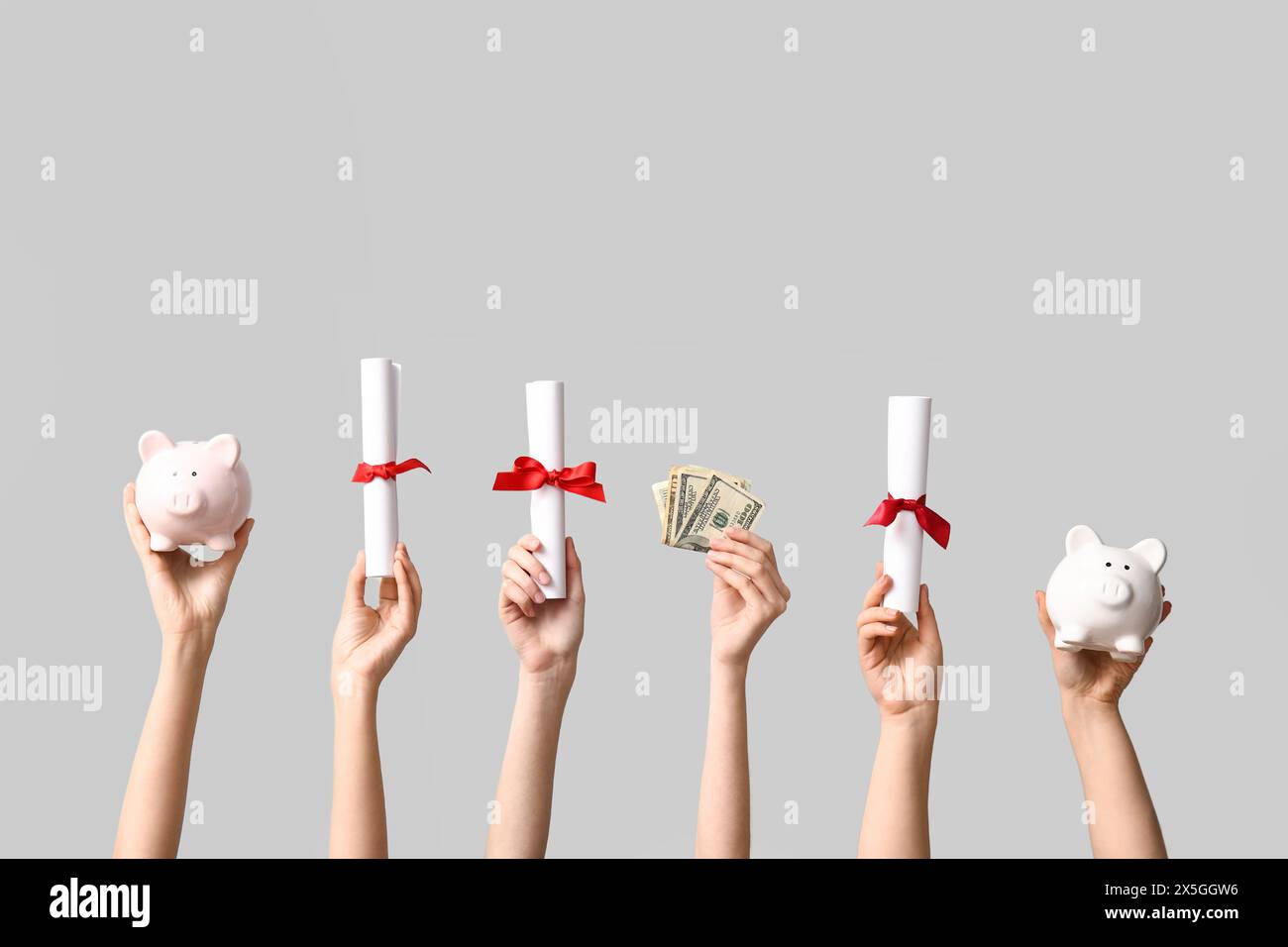Female hands holding diplomas, money and piggy banks on white ...