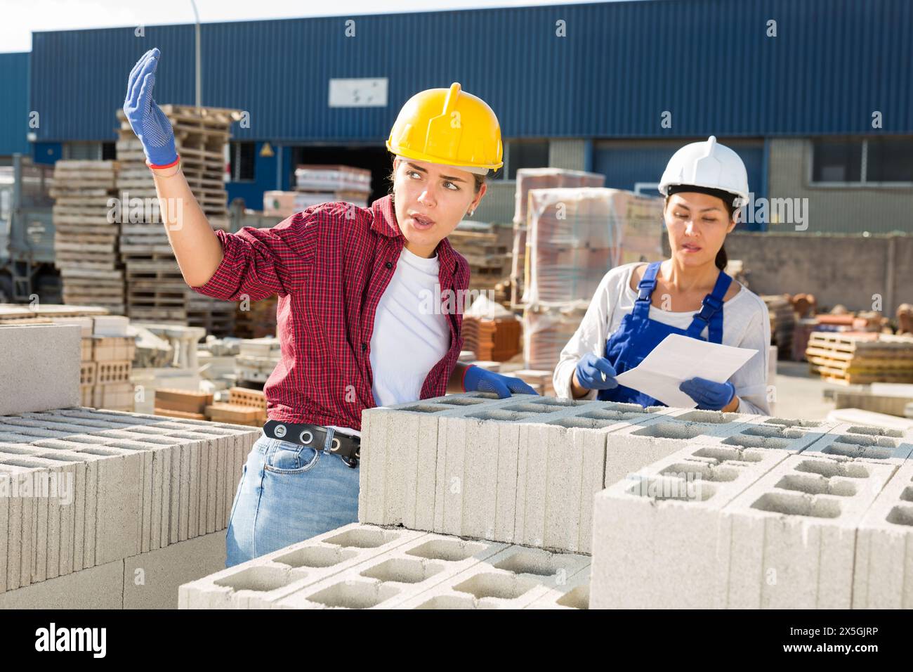 Worker stacking bricks in warehouse of building materials on an open ...